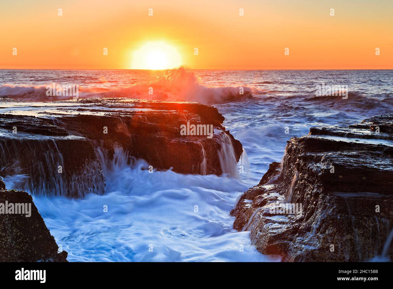 Rising sun over Pacific ocean horison above sandstone rocks of Sydney ...