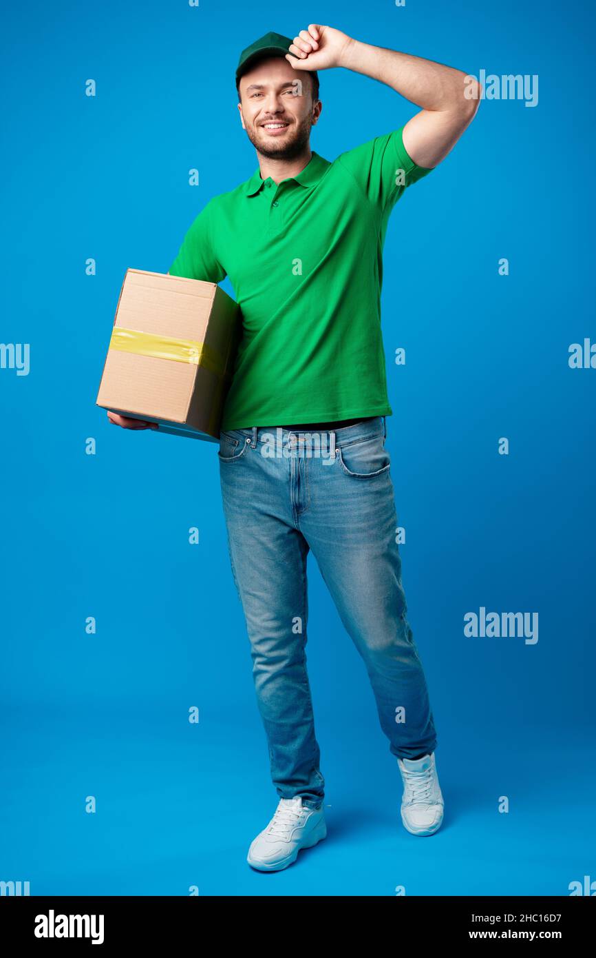 Delivery man with box in studio against blue background Stock Photo - Alamy