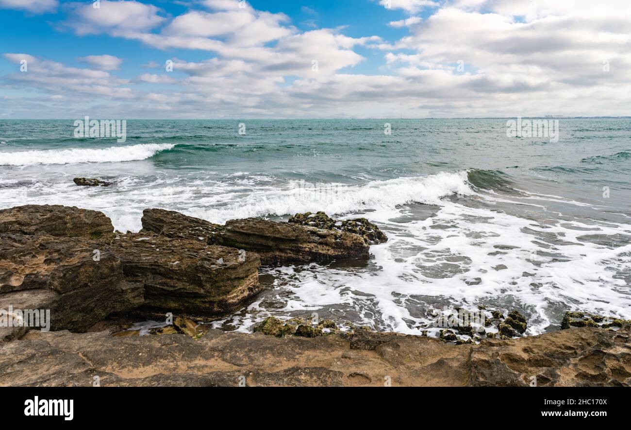 Waves breaking against coastal rocks scene Stock Photo - Alamy