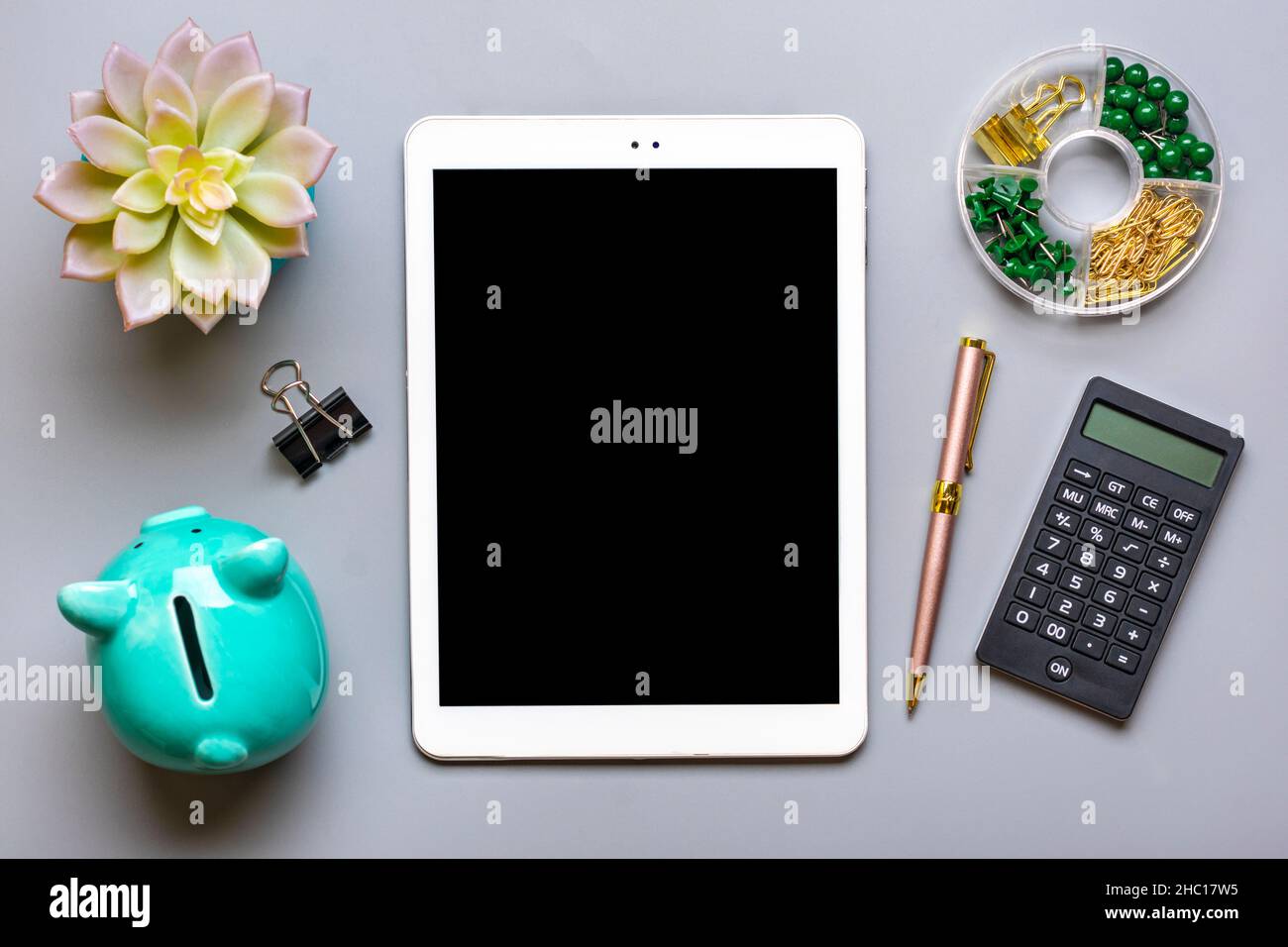 digital tablet with black screen, piggy bank, calculator, succulent ...