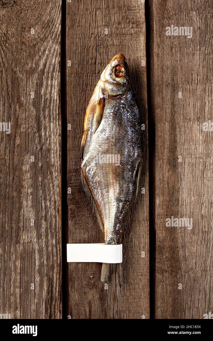 Salted sun-dried roach fish with label on tail on rough wooden ...