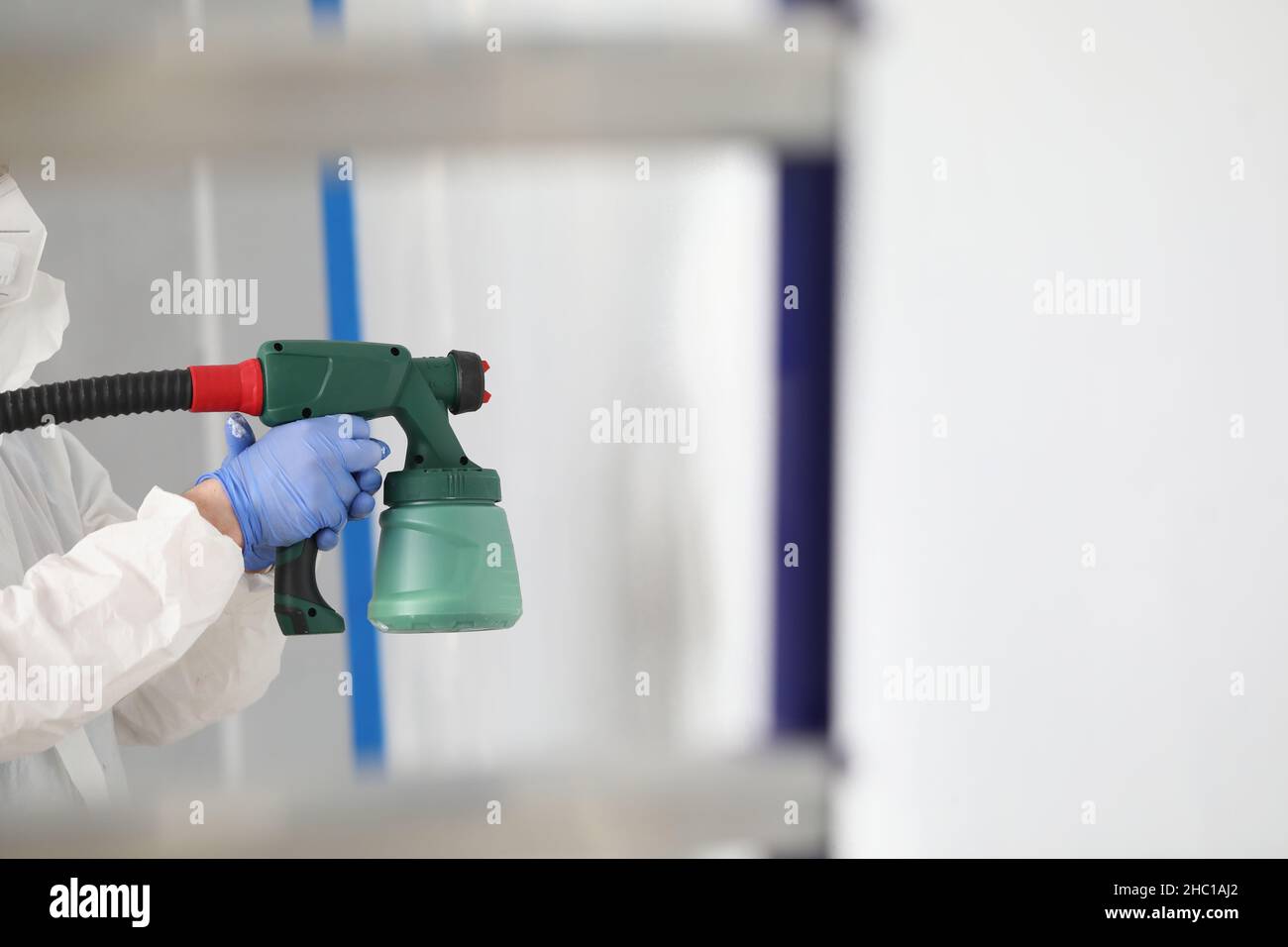 Worker use spray gun for coloring wall in white colour, renovation ...