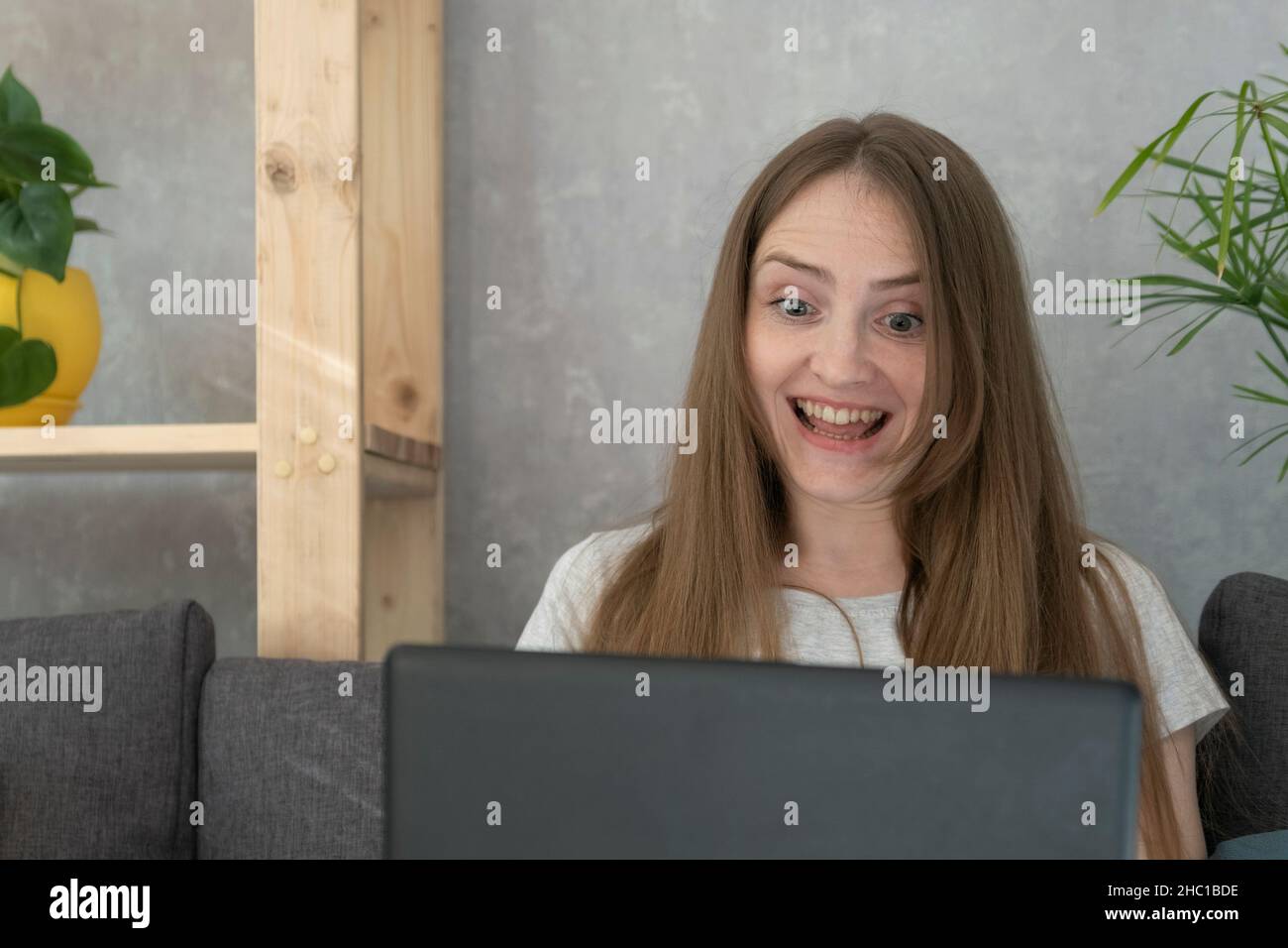 Young woman looking into laptop monitor and smiling. Surprised girl ...