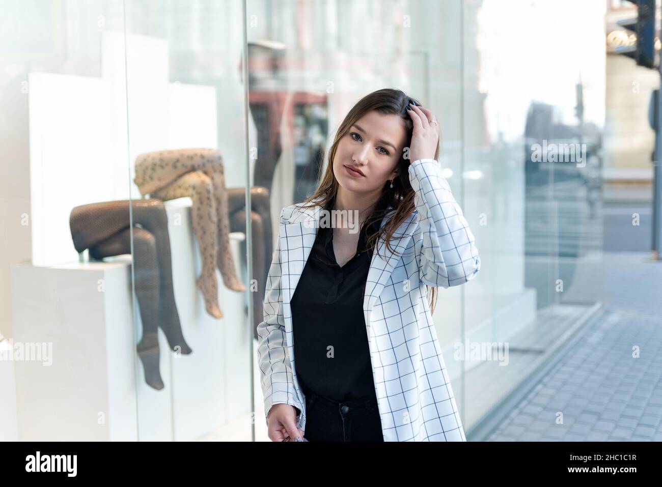Young stylish woman walks through the mall. Portrait of girl on window ...