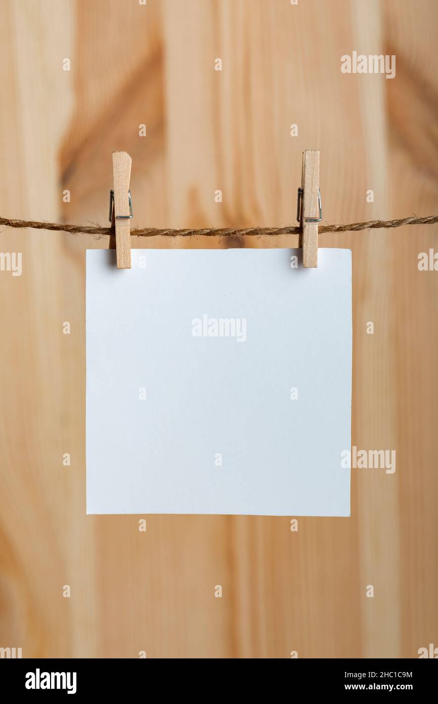 White blank sheet of paper hanging with clothespins on rope on wooden ...