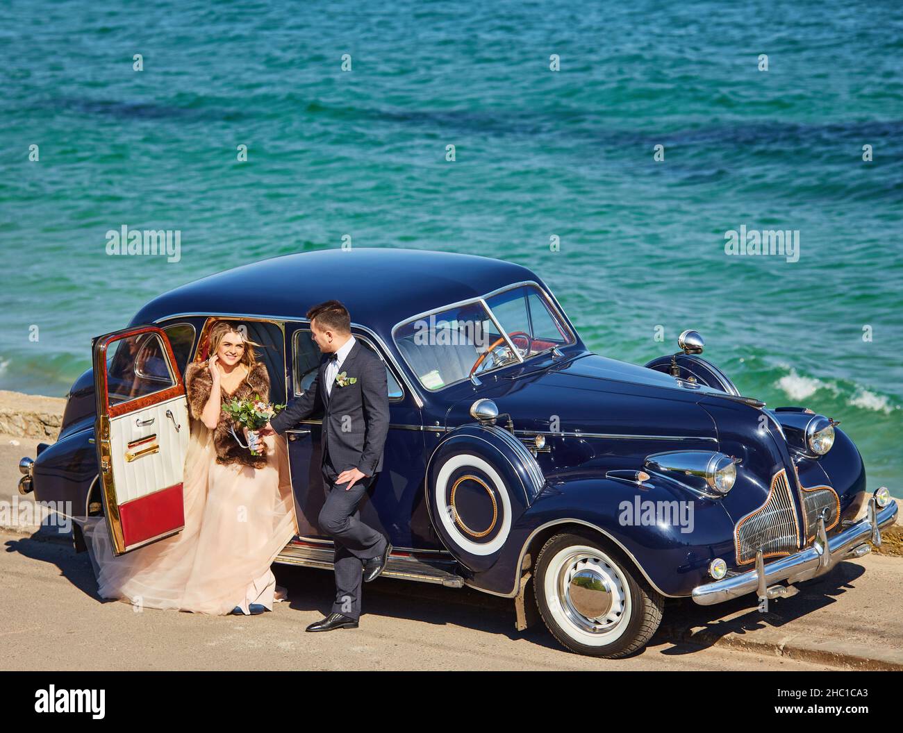 Happy bride and groom hugging and posing near old retro car before ...