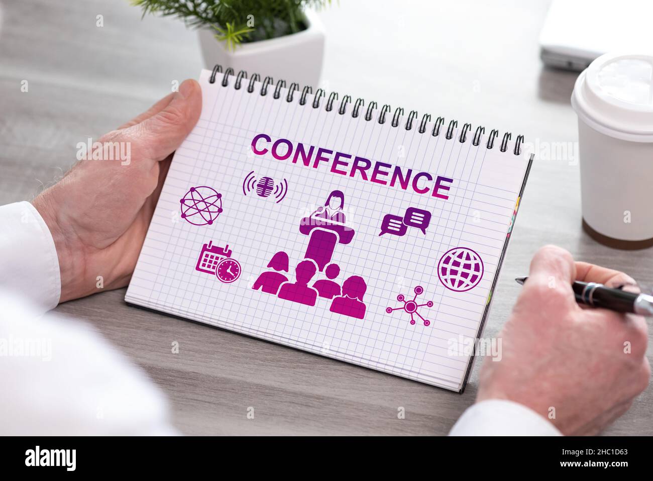 Hand holding a notepad with conference concept Stock Photo - Alamy