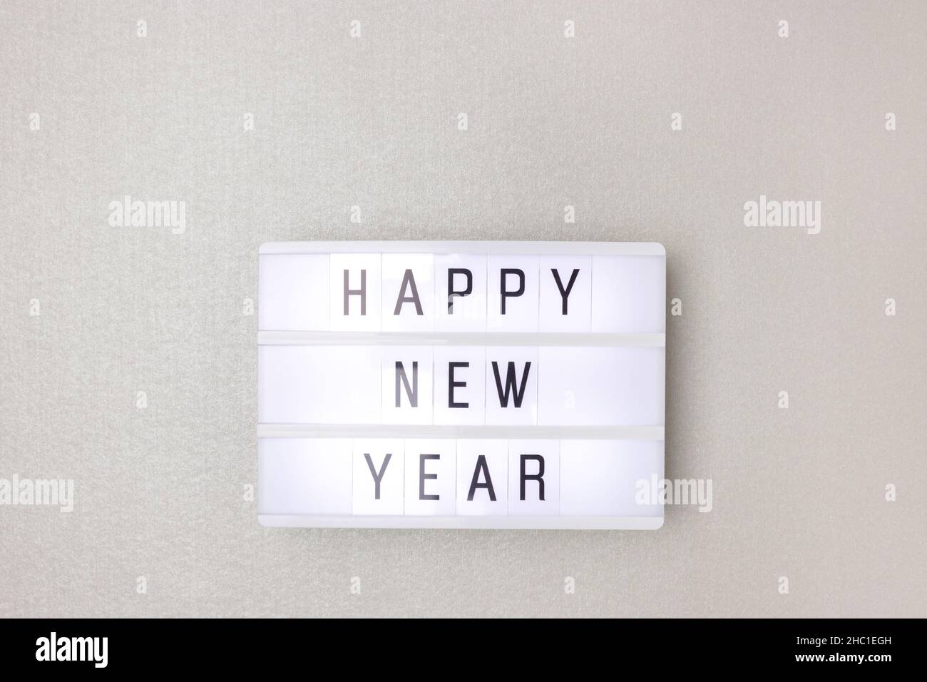 Happy New Year. White lightbox with phrase on a silver background with ...