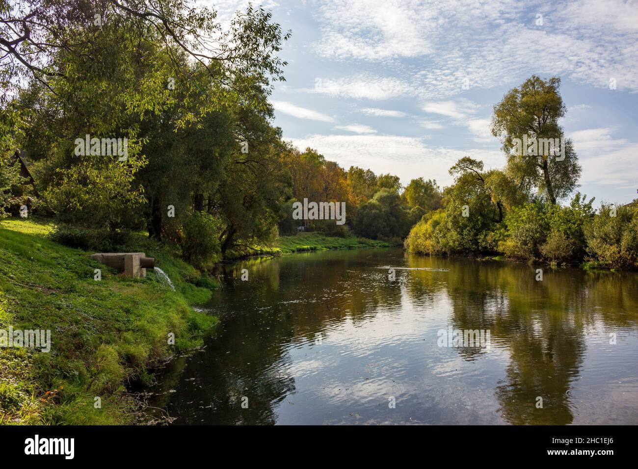 Beautiful landscape with a river bank and water discharge from a pipe ...