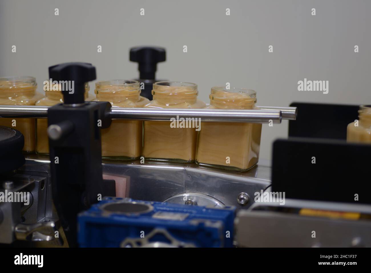 Jars of creamed honey in a packaging line at a commercial honey factory ...