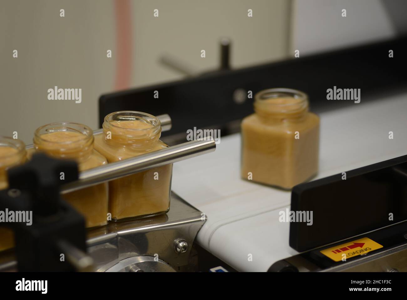 Jars of creamed honey in a packaging line at a commercial honey factory ...