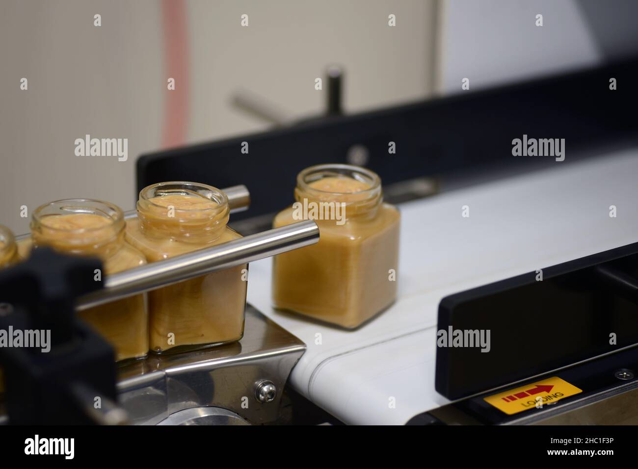 Jars of creamed honey in a packaging line at a commercial honey factory ...