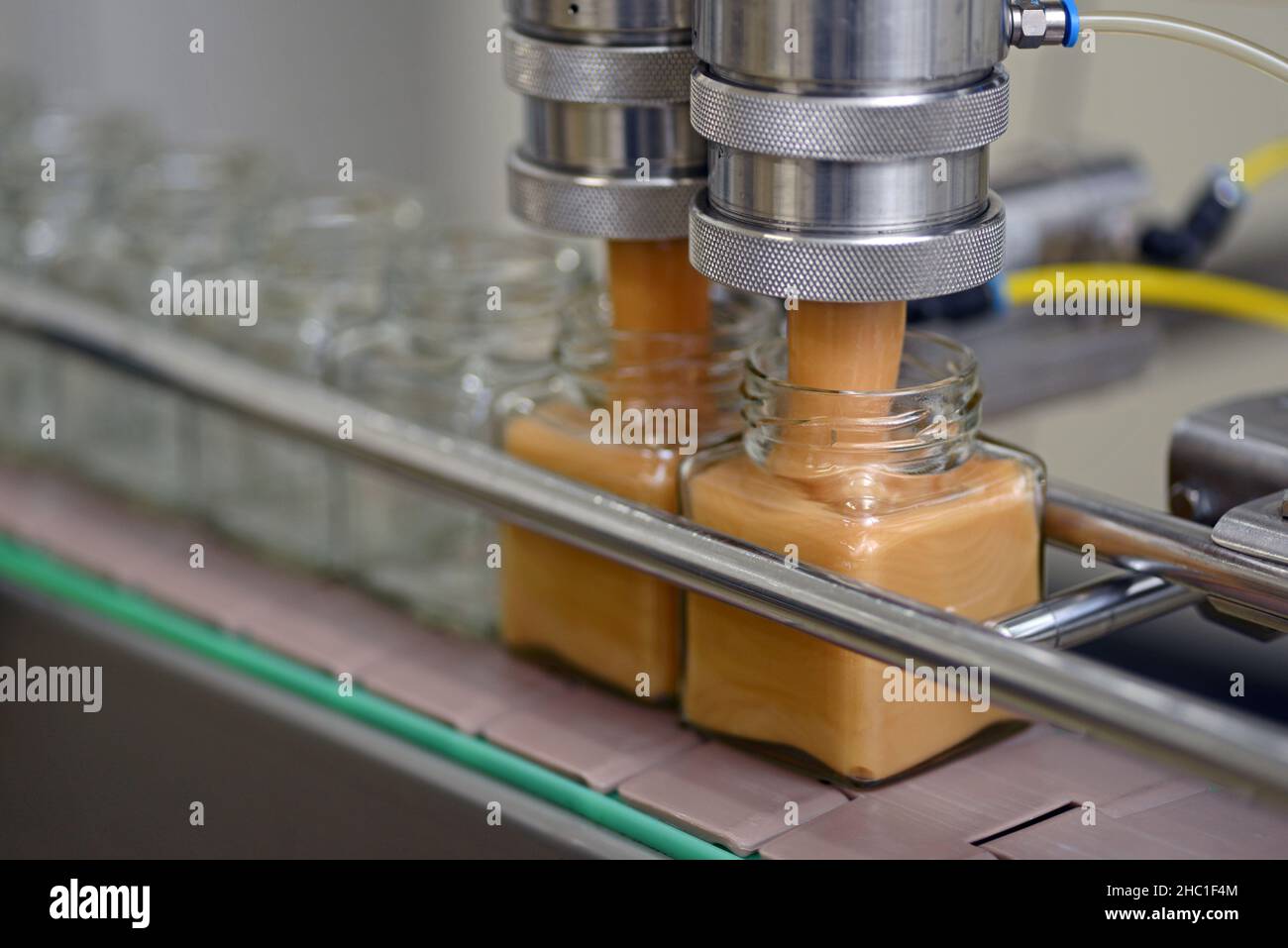 Jars of creamed honey in a packaging line at a commercial honey factory ...