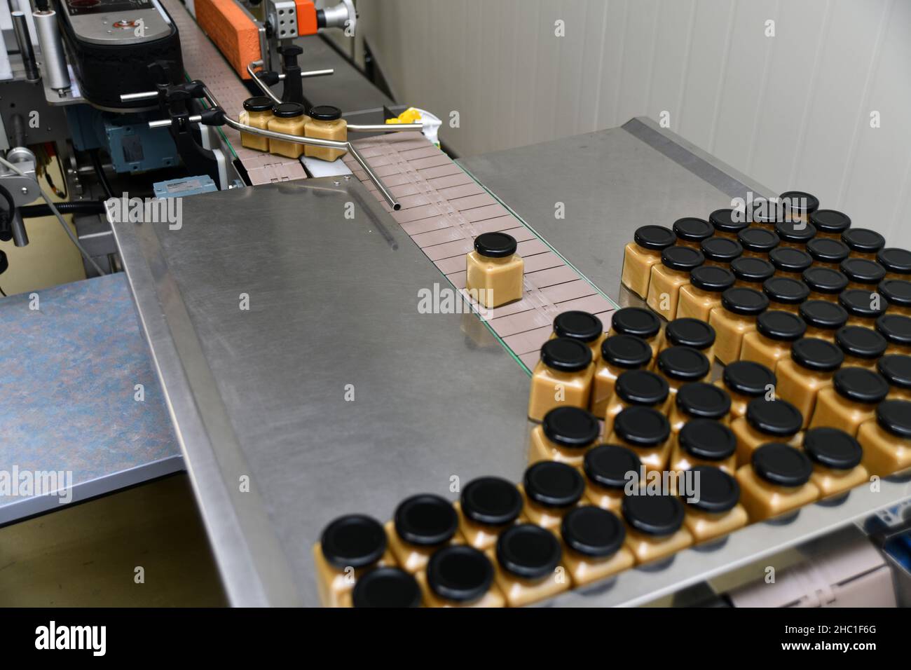 Jars of creamed honey in a packaging line at a commercial honey factory ...