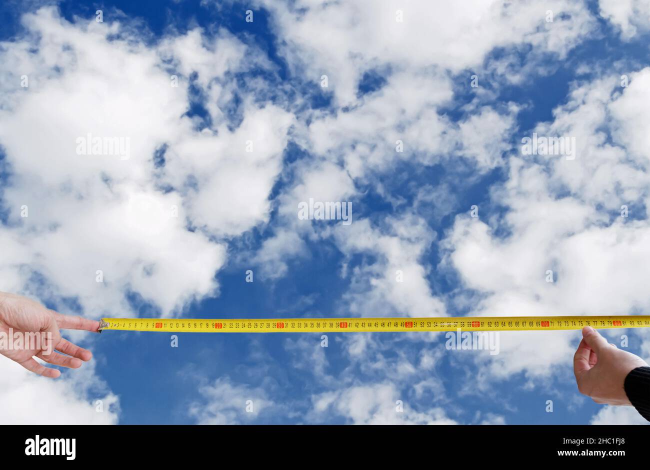 Measuring tool in hand against blue sky background with cumulus clouds ...