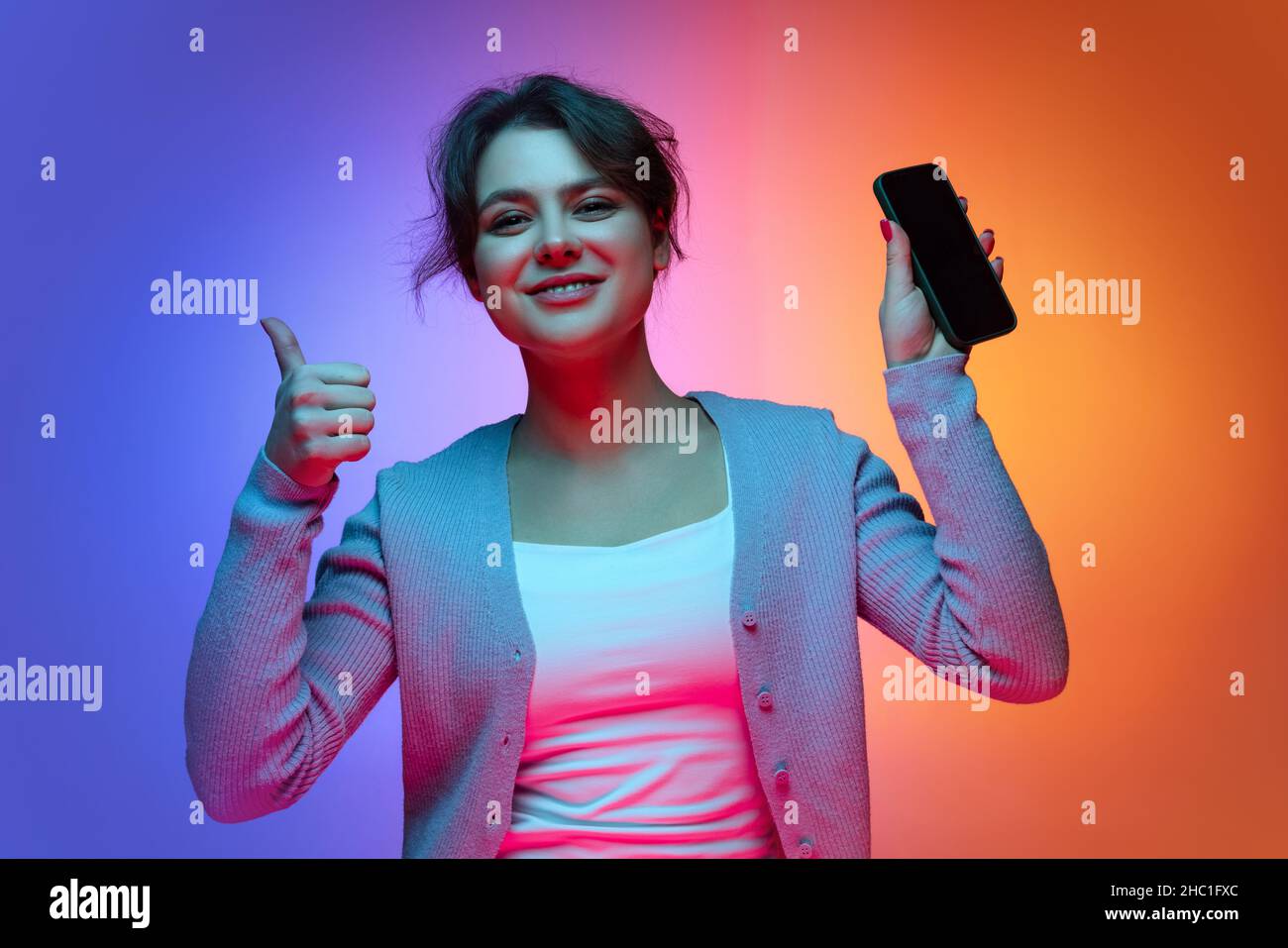 Happy young pretty girl in warm gray cardigan with phone isolated on ...