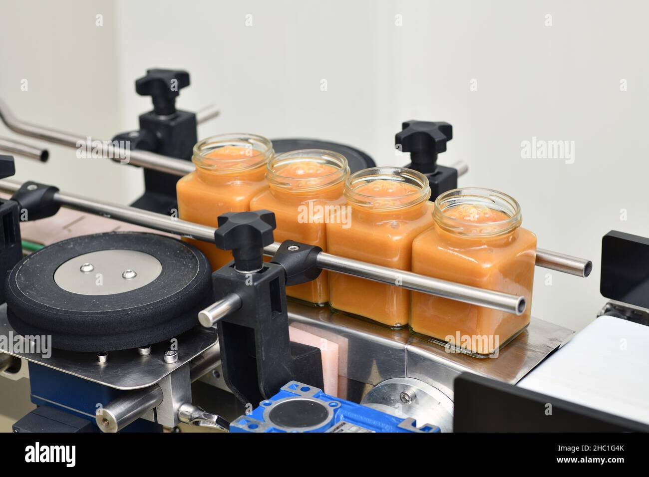 Jars of creamed honey in a packaging line at a commercial honey factory ...