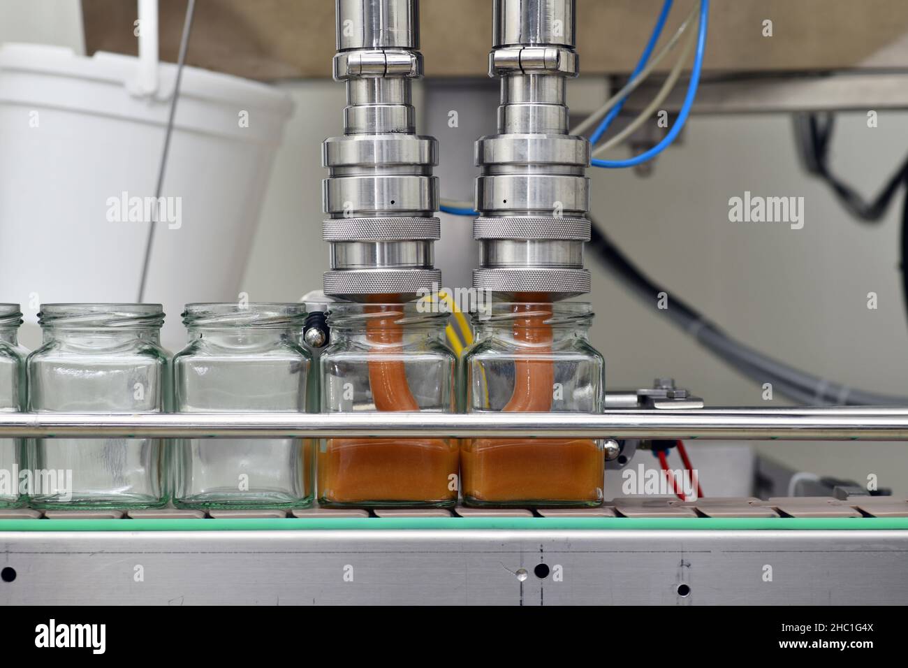 Jars of creamed honey being filled in a packaging line at a commercial ...