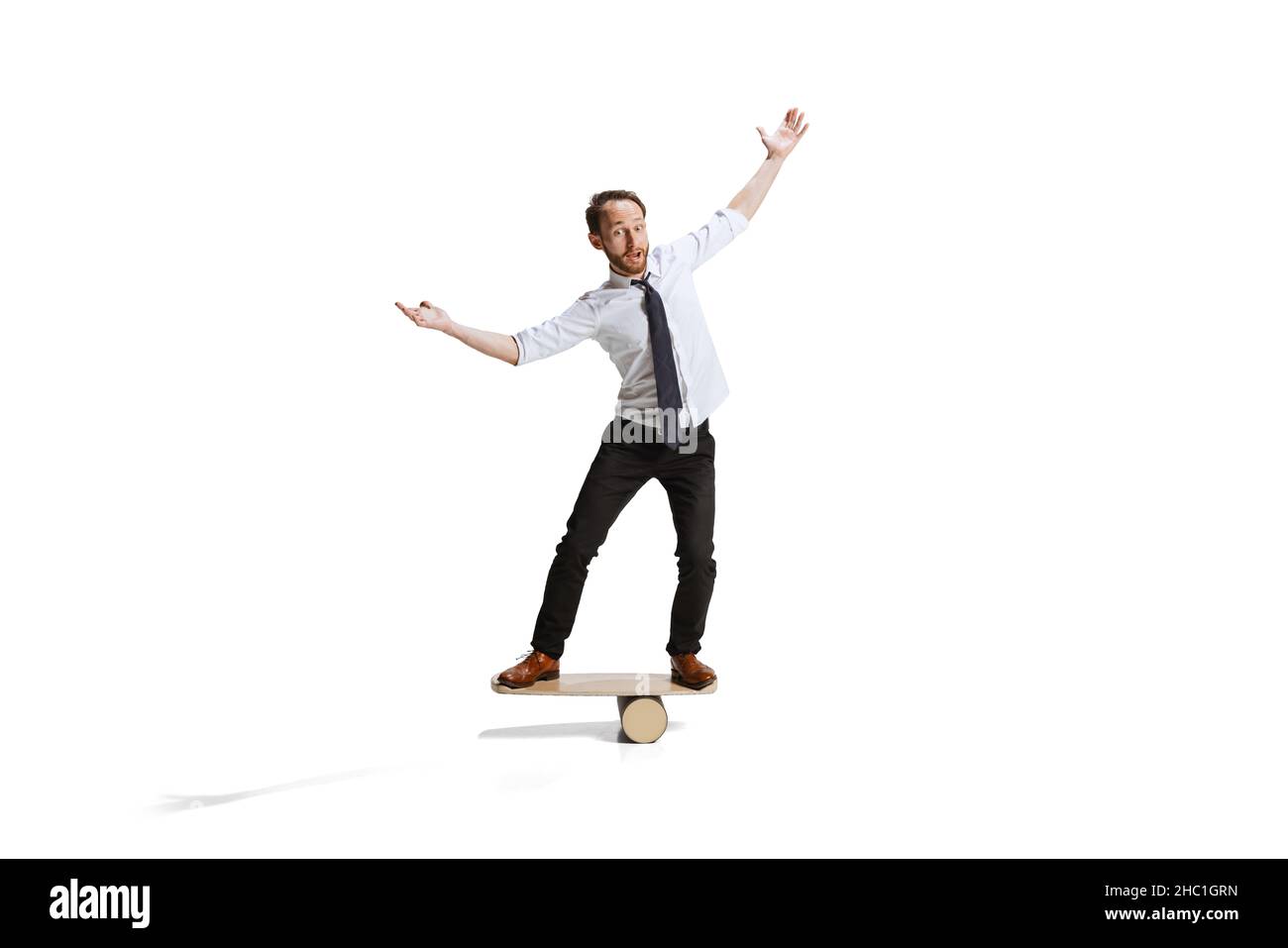 Full-length portrait of young man, office worker standing on balance ...