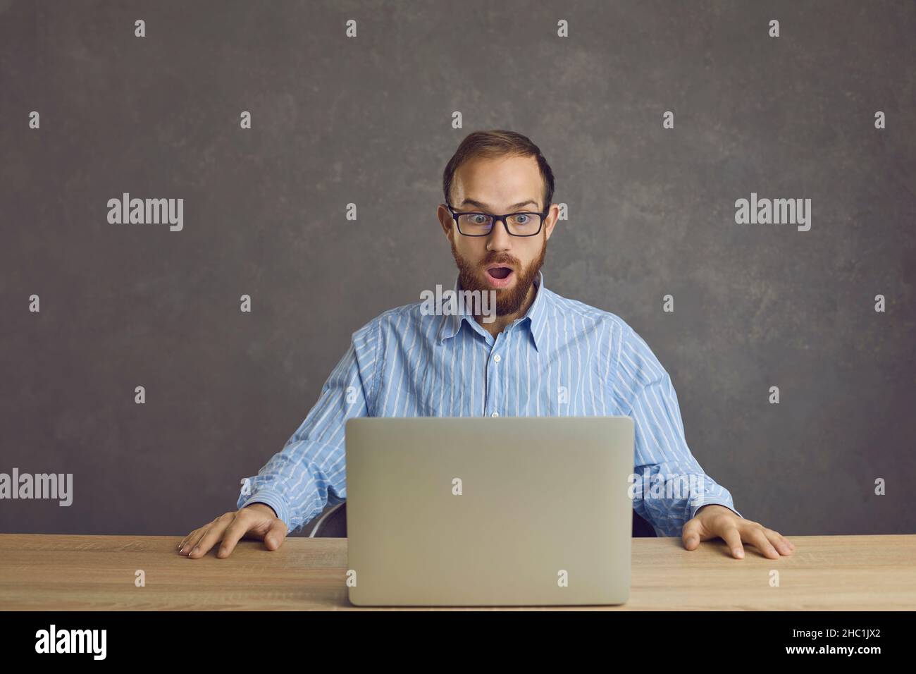 Man sitting at the table with a laptop is very shocked by what he saw ...