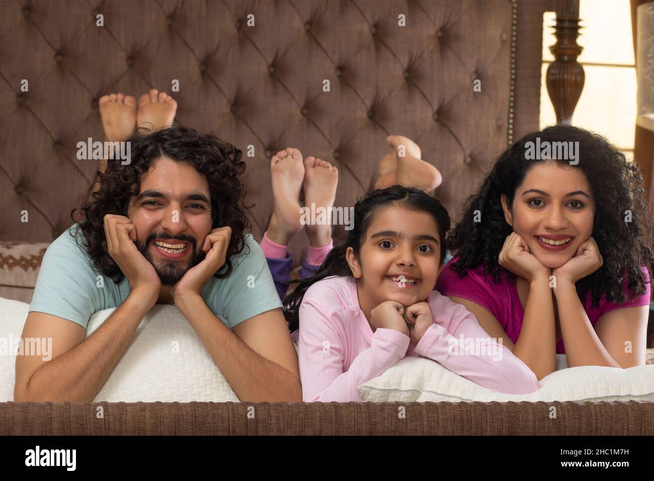 Happy family members posing together while lying on bed Stock Photo - Alamy