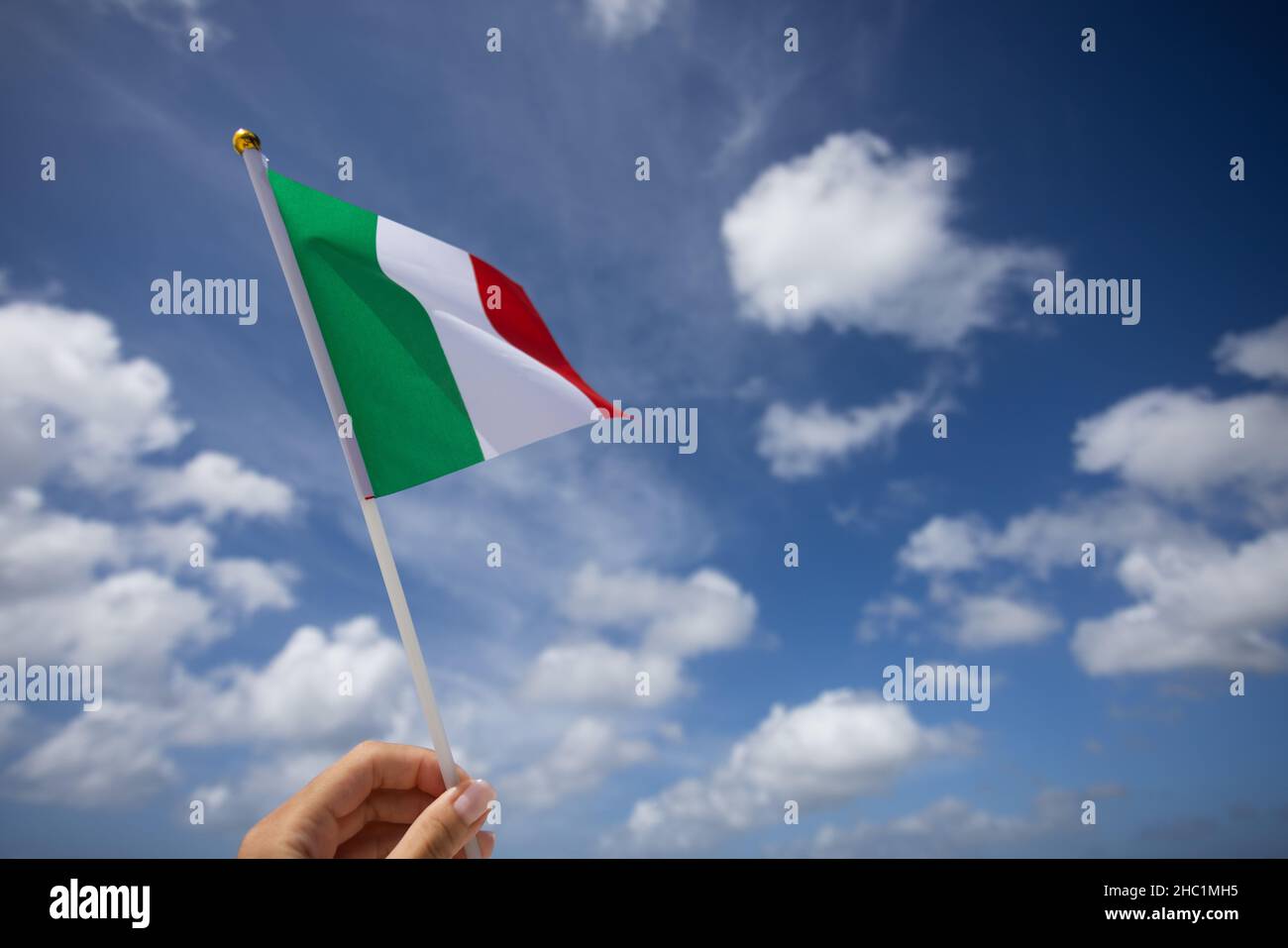Italian flag waving in the wind in a female hand on a blue sky with ...