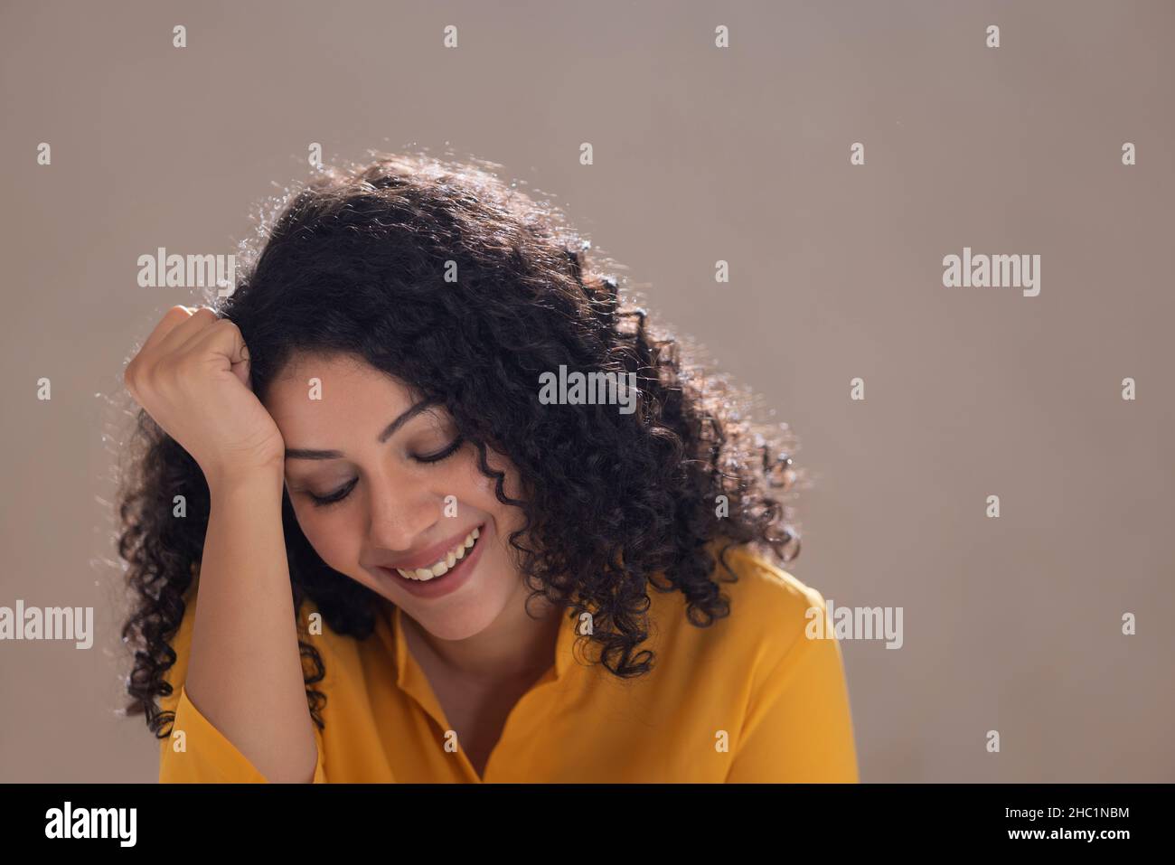 Young woman with hand on head looking down and smiling Stock Photo - Alamy