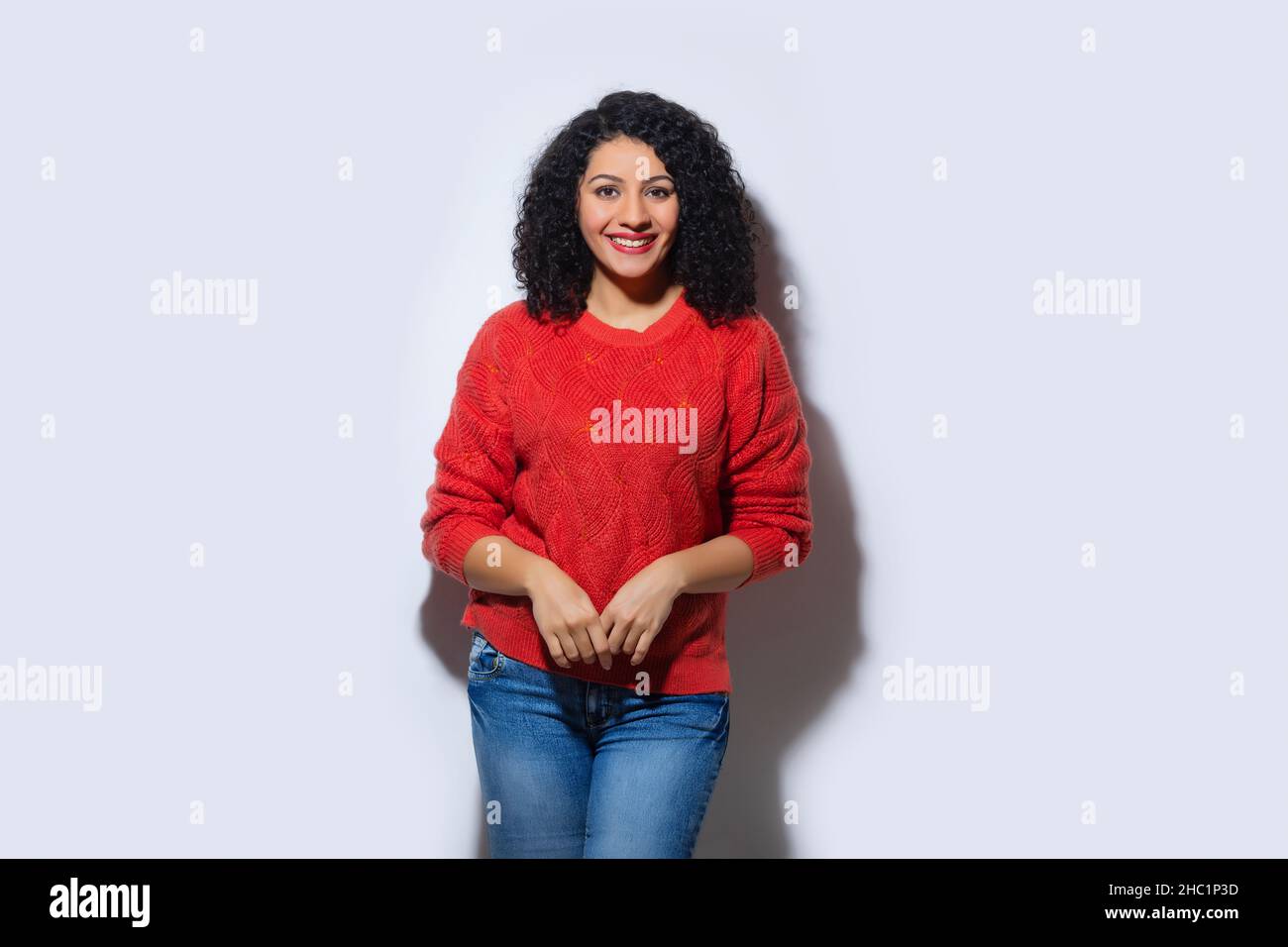 Young woman in red sweater standing and smiling Stock Photo - Alamy
