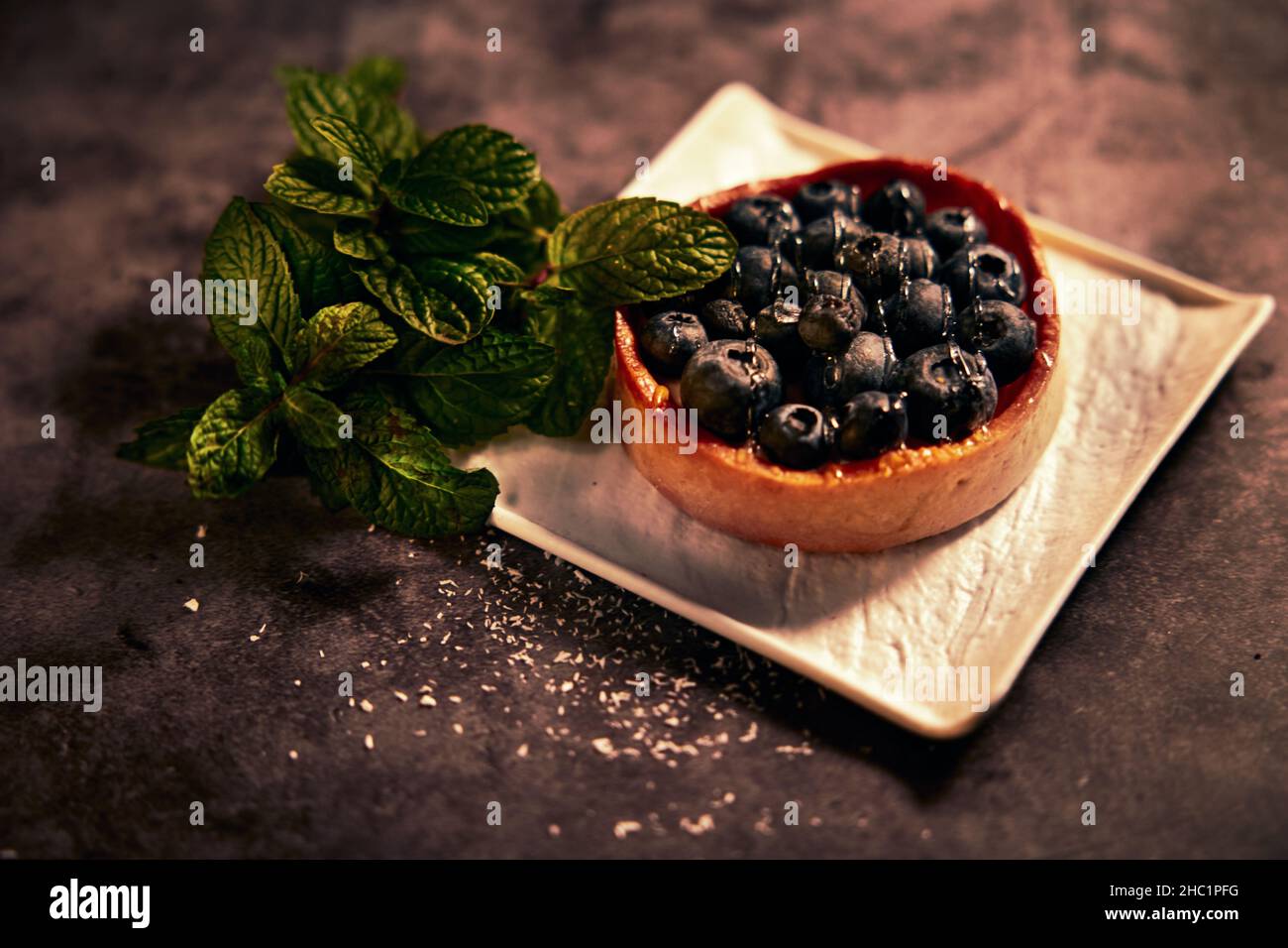 Cake basket with blueberries on a white ceramic plate with mint leaves ...