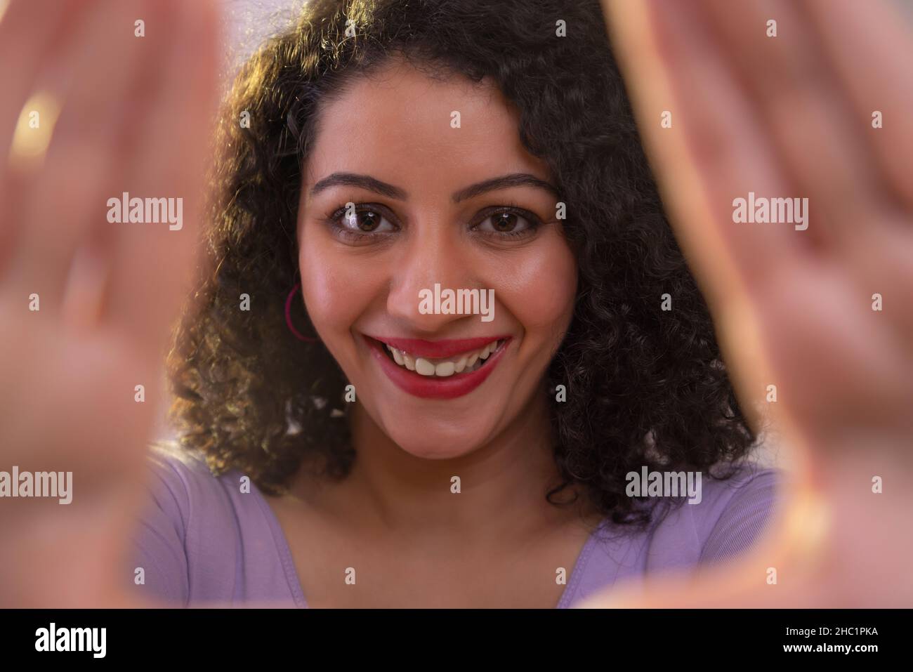 Adult woman forming frame with her hands and looking at camera through ...