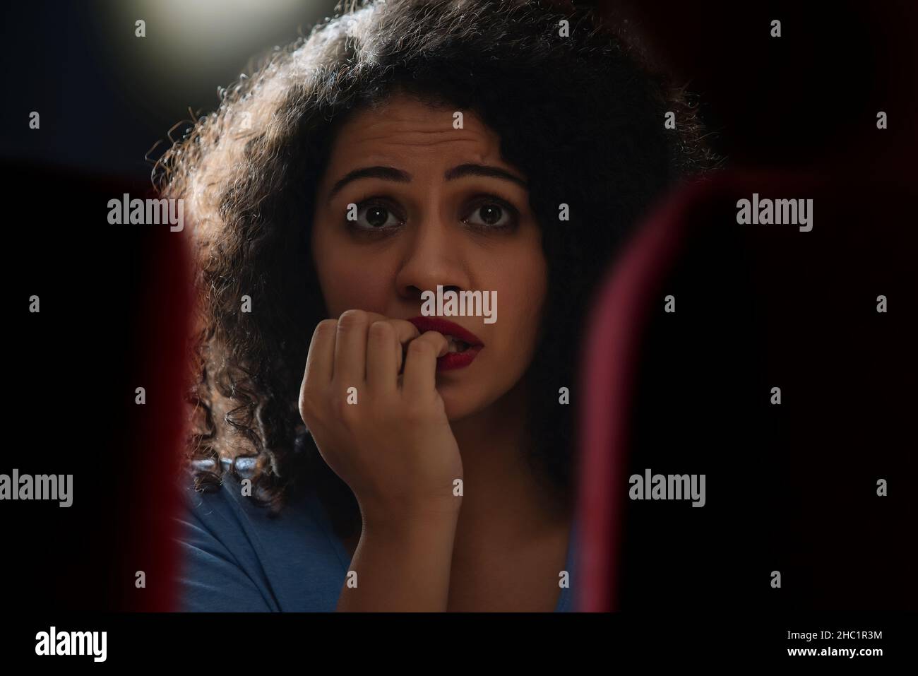 Portrait of a shocked and surprised woman while watching horror movie ...