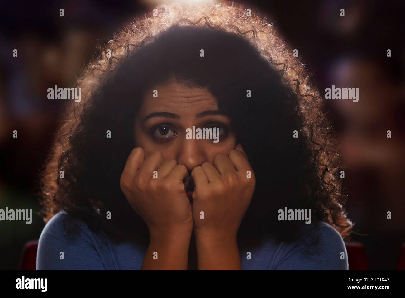 Portrait of a shocked and surprised woman while watching horror movie ...