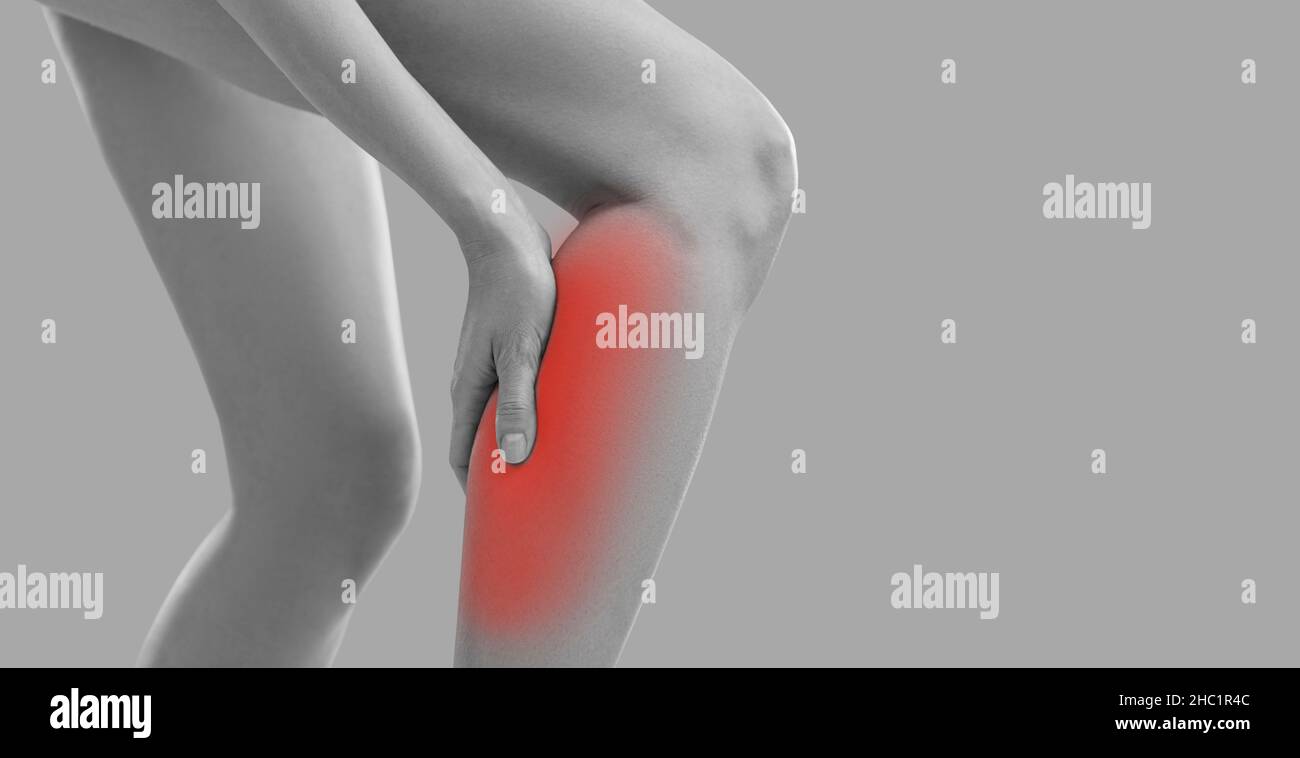 Young woman touches her calf as she has leg cramp or feels pain in her ...