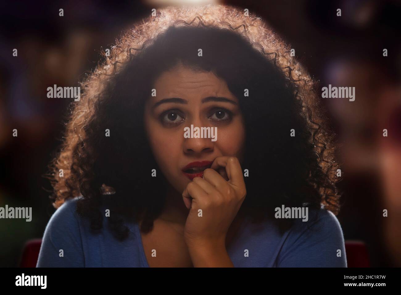 Portrait of a shocked and surprised woman while watching horror movie ...