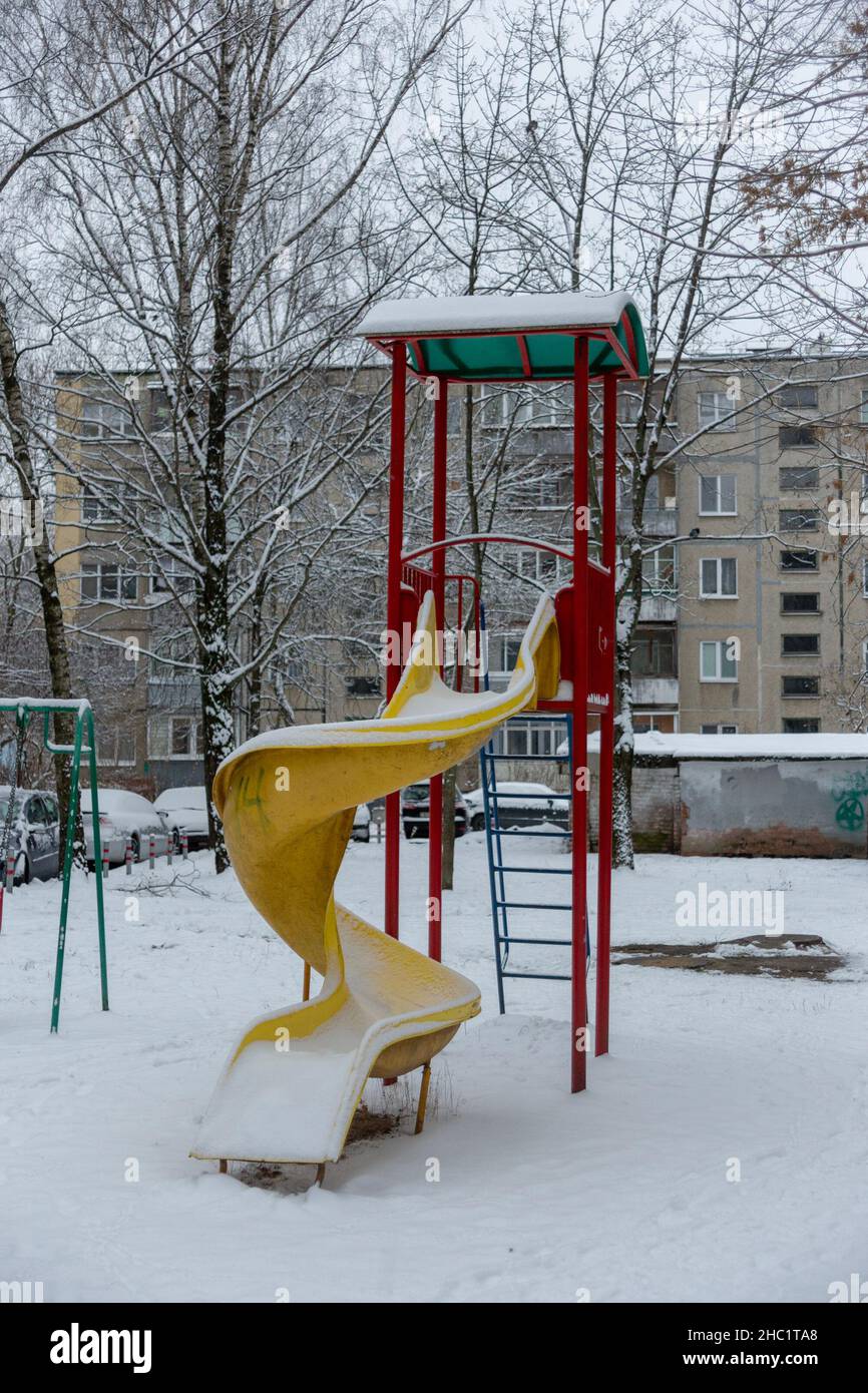 Snow-covered children's slide in the courtyard of a residential area ...