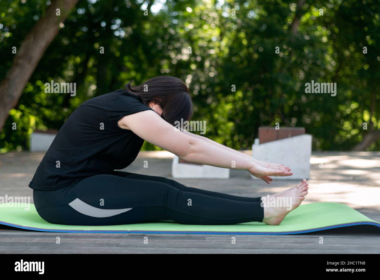 Young beautiful flexible girl makes a lean forward with her hands from ...
