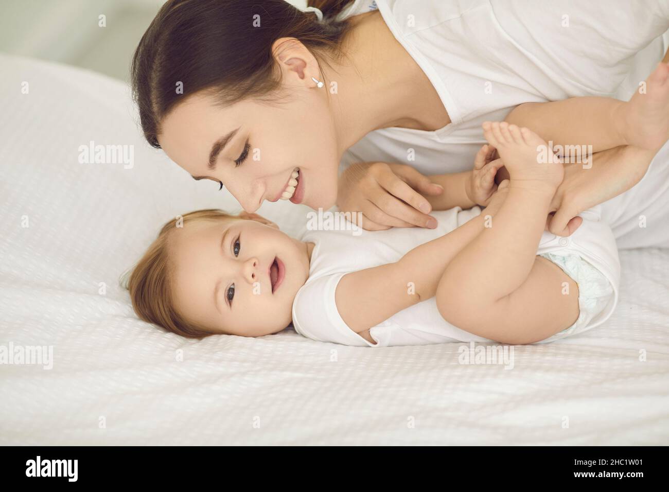 Happy mother and her cute smiling baby are playing and cuddling on a ...