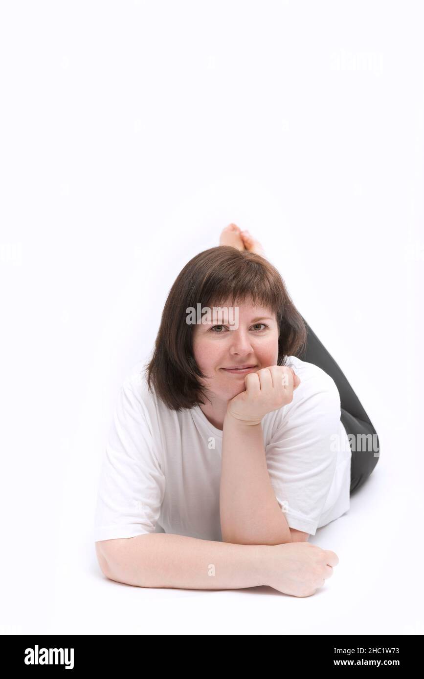 Young dark-haired woman lies on stomach with her hand prop up head ...