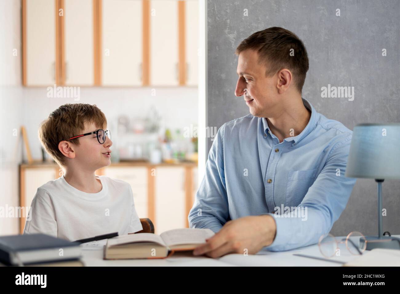 Father and son study school subjects at home. Young teacher teaches a ...