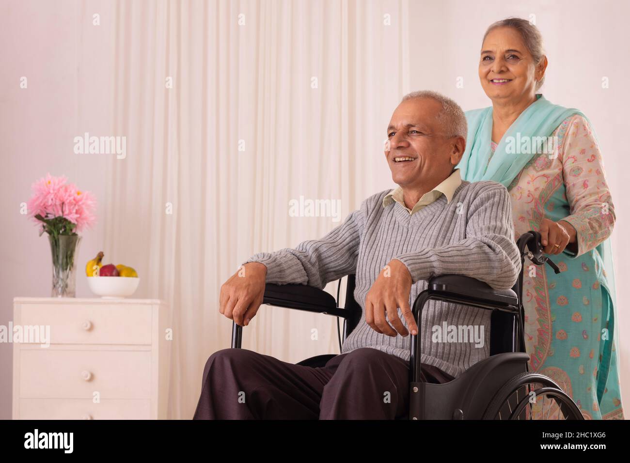 Senior woman moving her husband sitting on wheel chair Stock Photo - Alamy