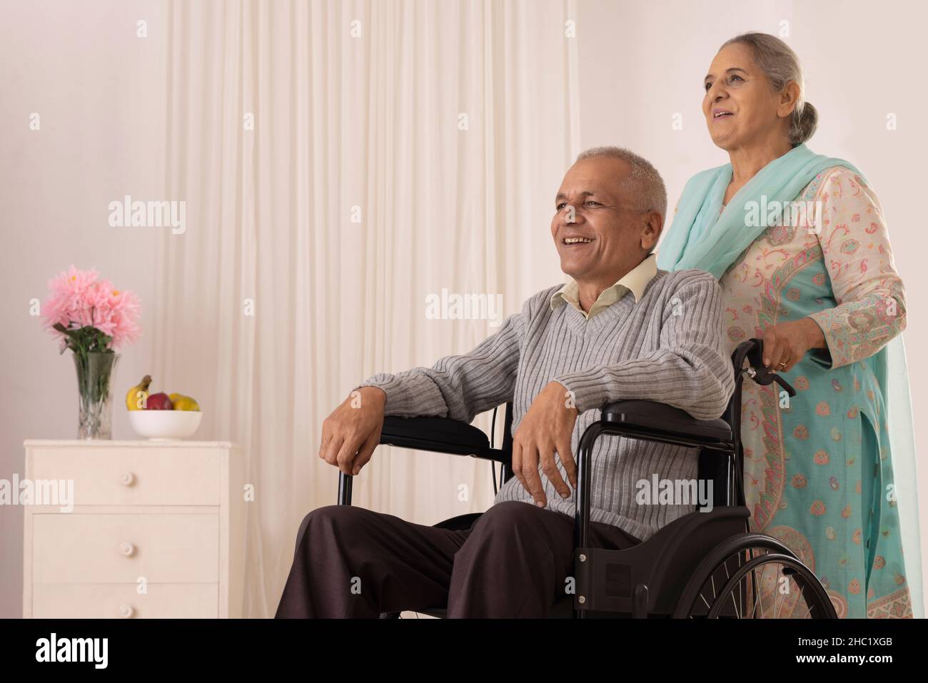 Senior woman moving her husband sitting on wheel chair Stock Photo - Alamy