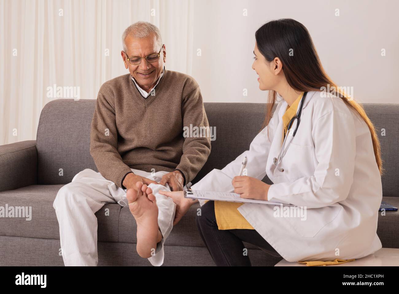 Lady doctor checking old man having knee problem Stock Photo - Alamy