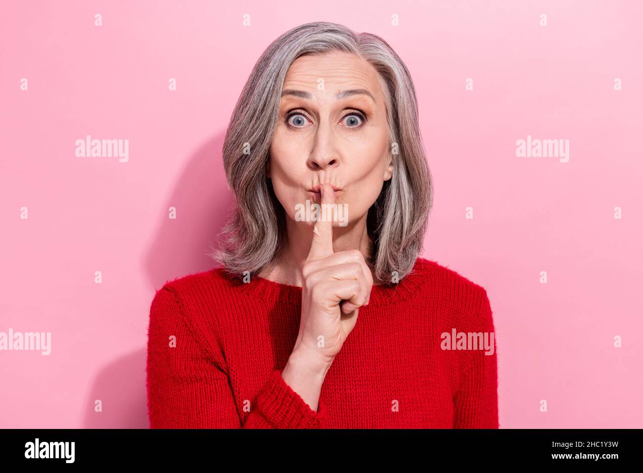 Portrait of attractive trendy elderly gray-haired woman showing shh ...