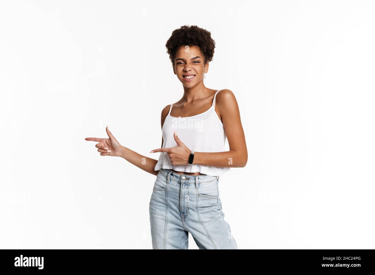 Young black woman in tank top smiling and pointing finger aside ...