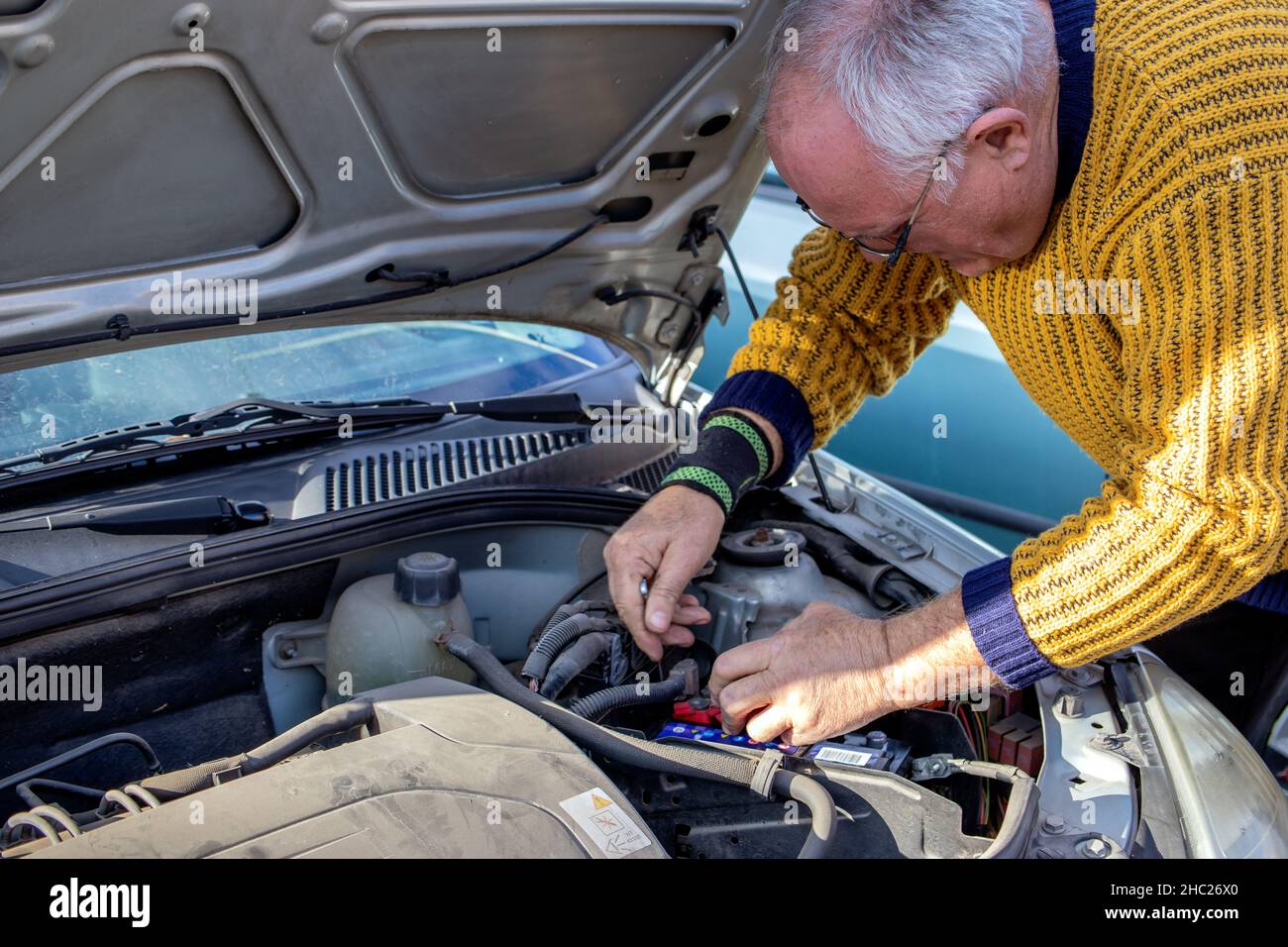 Senior mechanic worker checking and changing a car battery. Old car ...