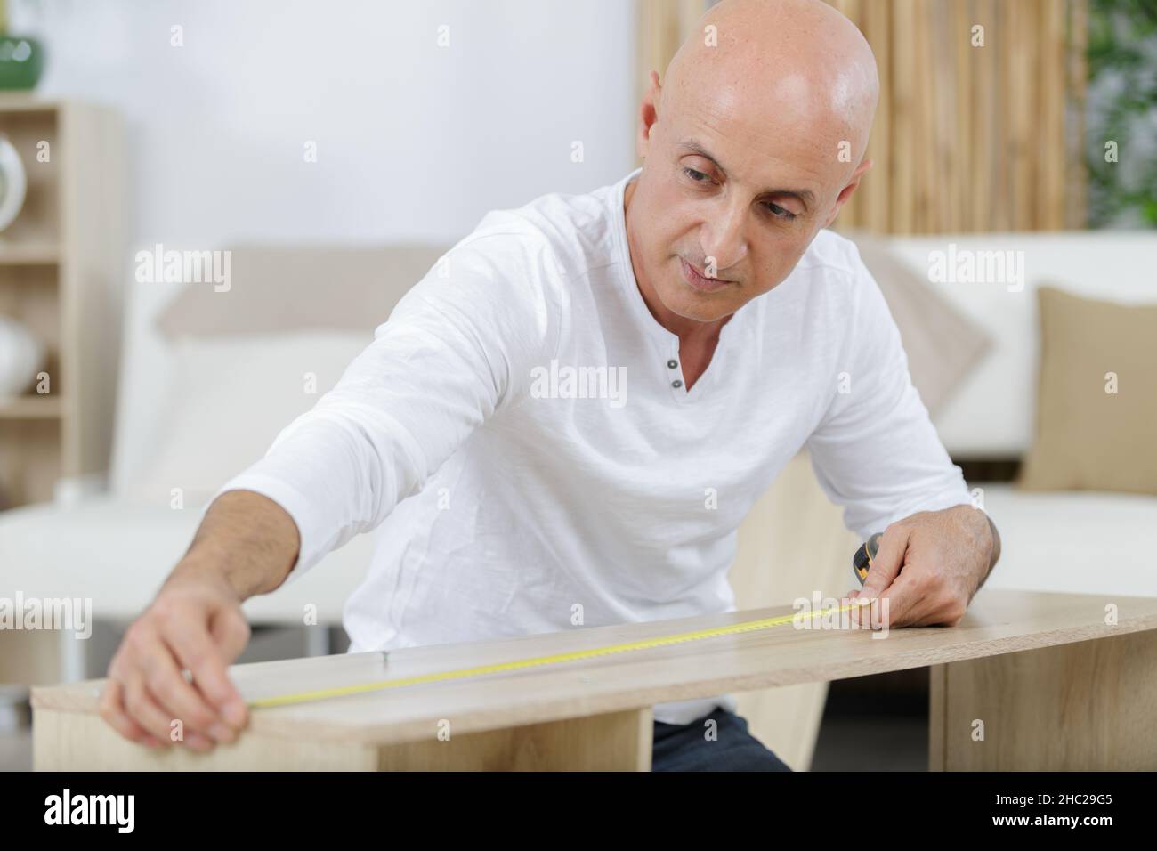 man measuring home furniture with measure tape Stock Photo - Alamy