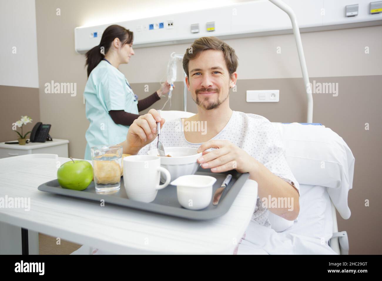 male patient in hospital bed eating meal from tray Stock Photo - Alamy