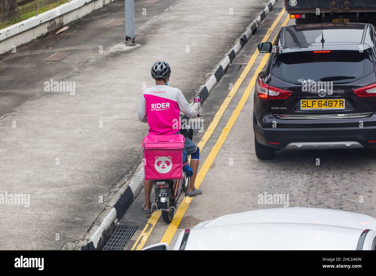 A food delivery rider with safety helmet on is riding his electric ...