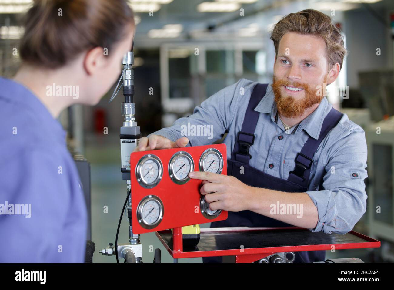 engineer helping female apprentice in factory Stock Photo - Alamy