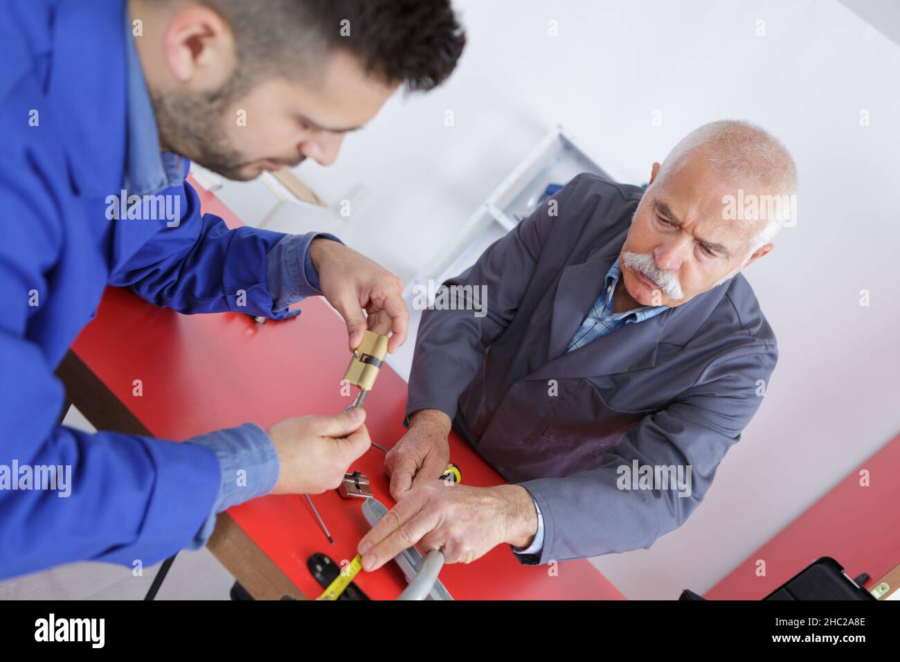 two workmen fitting replacement lock mechanism in interior door Stock ...